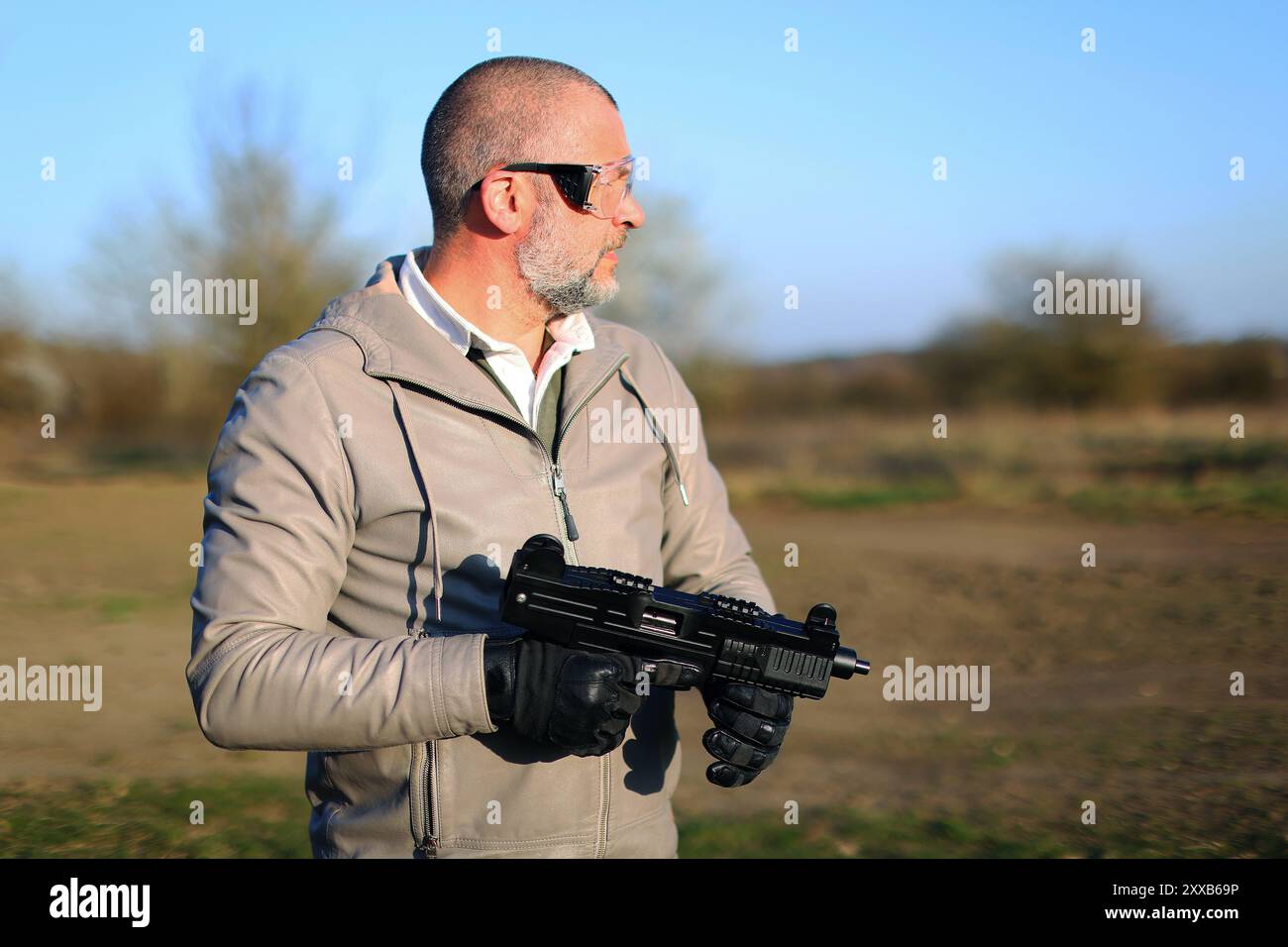 Man with gray jacket shooting black rifle on an openair shooting range ...