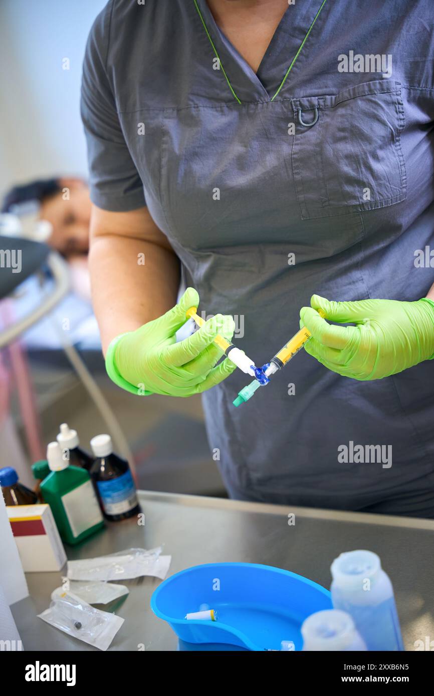 Clinic employee prepares a syringe with medicine for injection to a ...