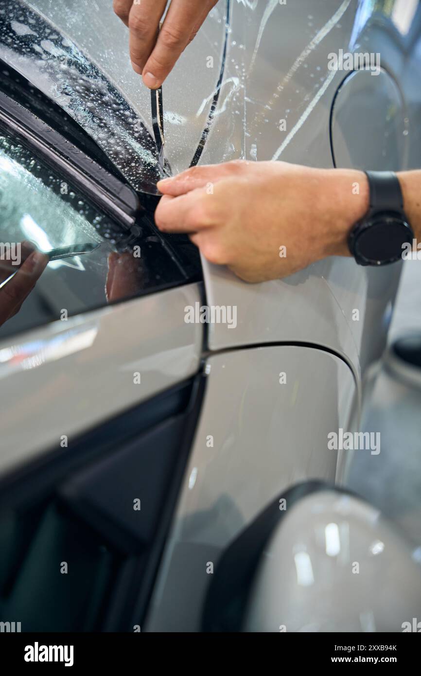 Man cuts off excess film on a car Stock Photo - Alamy