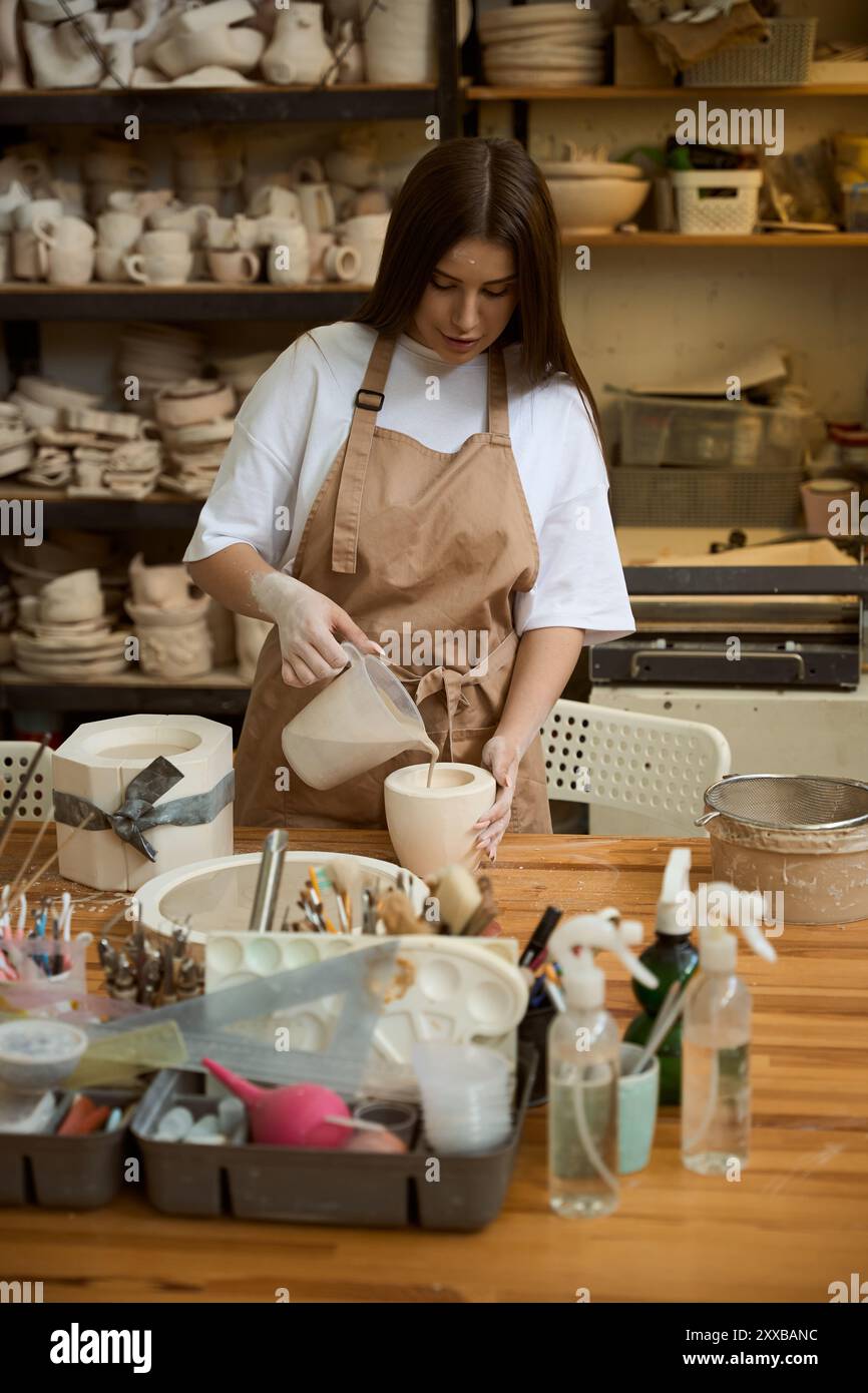 Female pottery artist pouring pottery mixture into mold for mug Stock ...