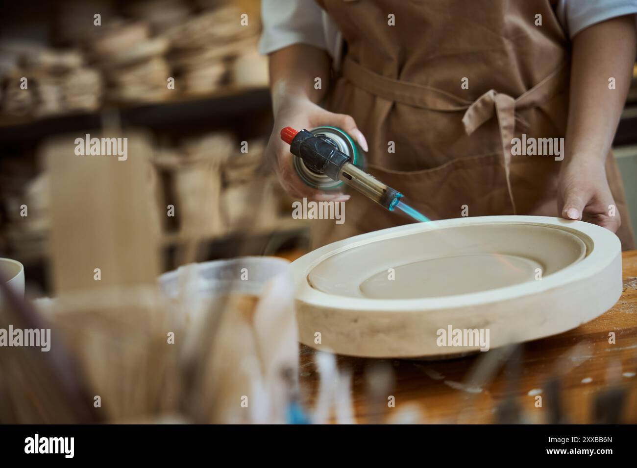 Woman in an apron drying earthenware plate using dryer tool Stock Photo ...
