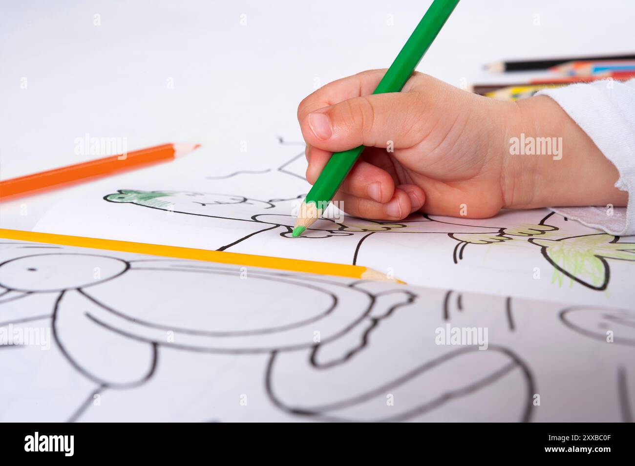 Childs hand with a green pencil working in a coloring book close up ...