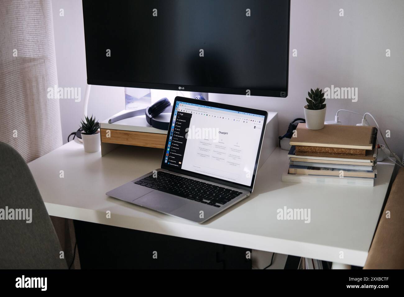 Home office desk with open laptop showing ChatGPT, monitor, and books ...