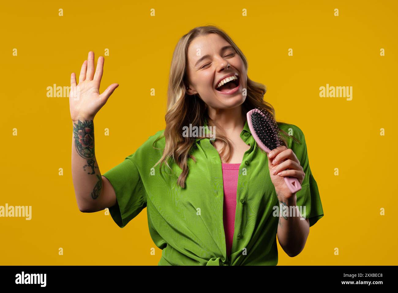 Woman singing, dancing with hair brush instead microphone on yellow ...