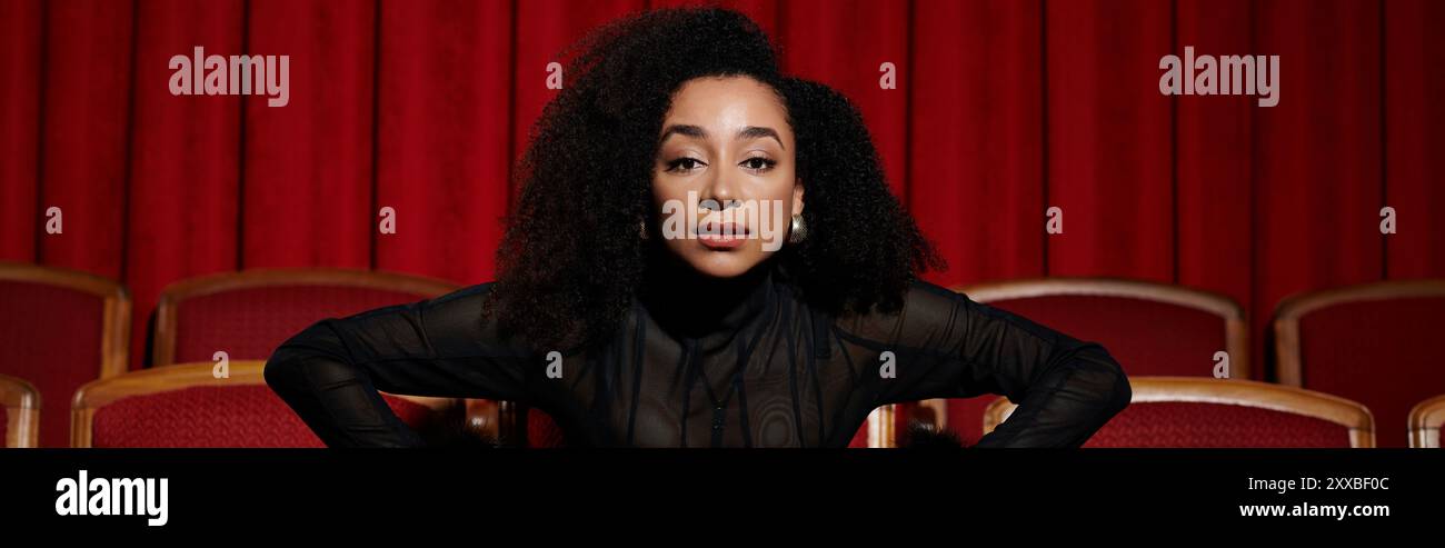 A stylish woman with curly hair watches a movie in a theater ...