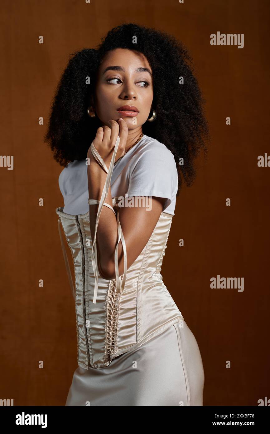 An elegant African American woman in a white top and cream corset poses ...