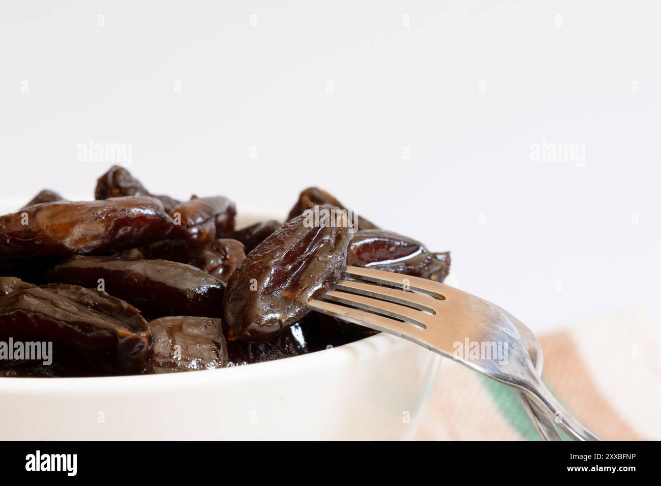 A portion of dates inside a white ceramic bowl photographed up close ...
