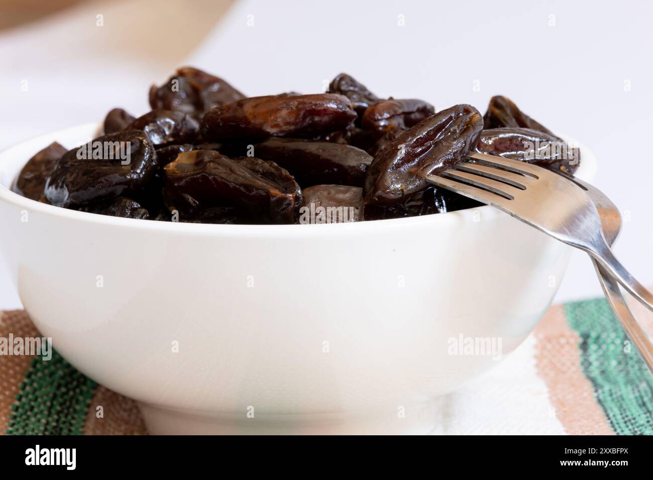 Portion of dried dates inside a white ceramic bowl photographed close ...