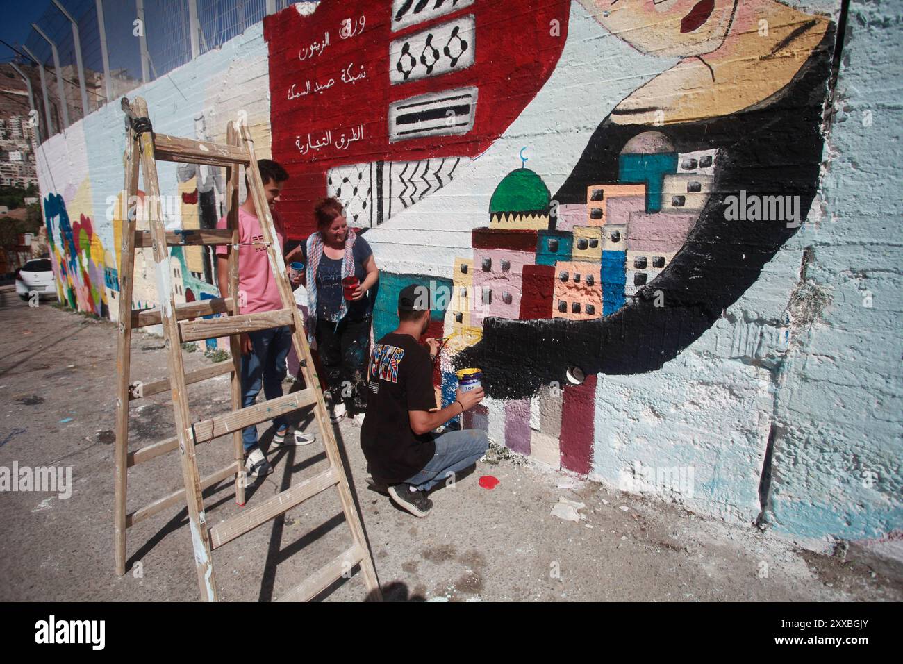 Palestinian artist Mays Abu Saa paints a mural of the Old City of ...