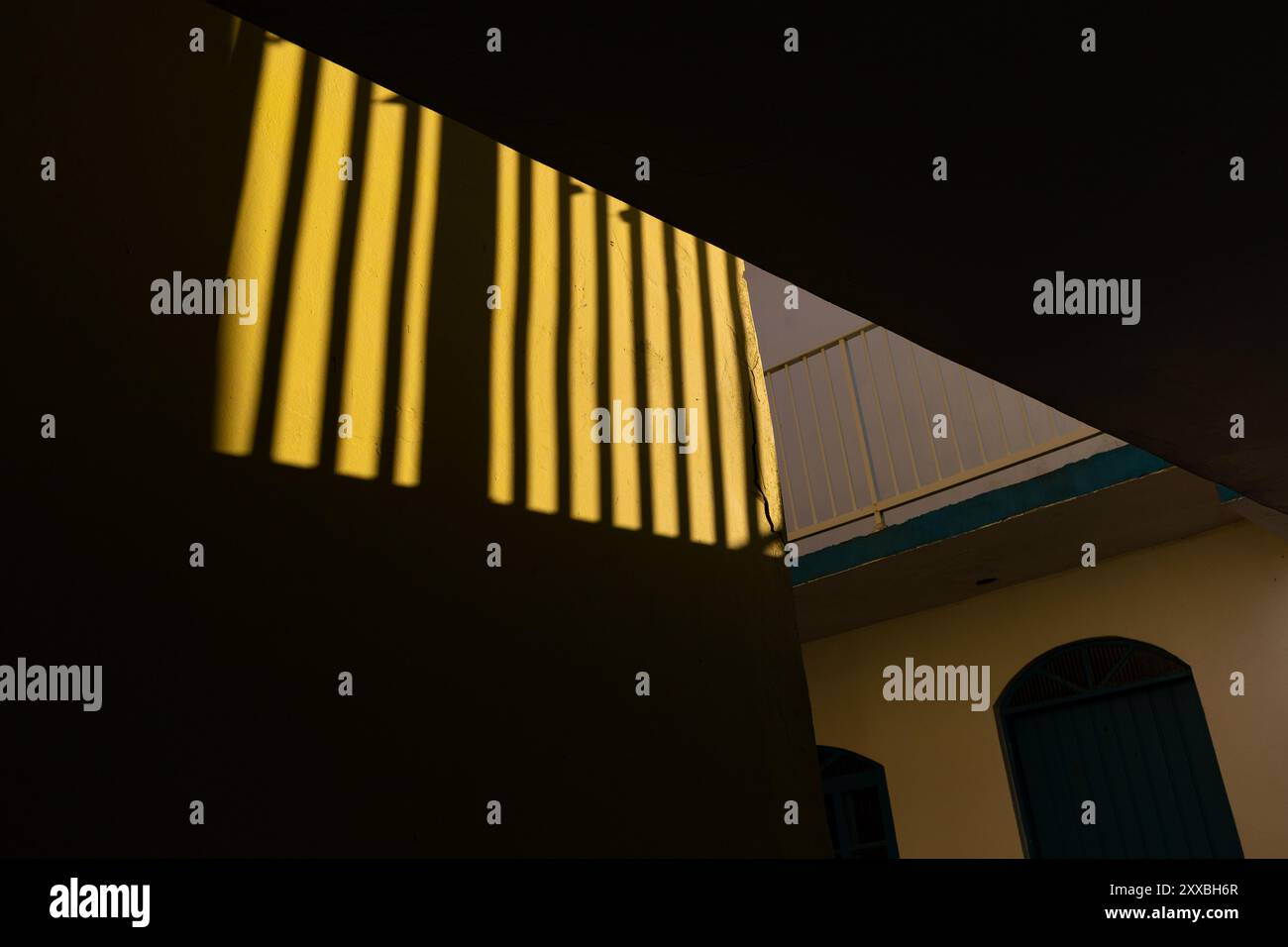 Sunlight casts dramatic shadows on a yellow wall, creating a striking ...