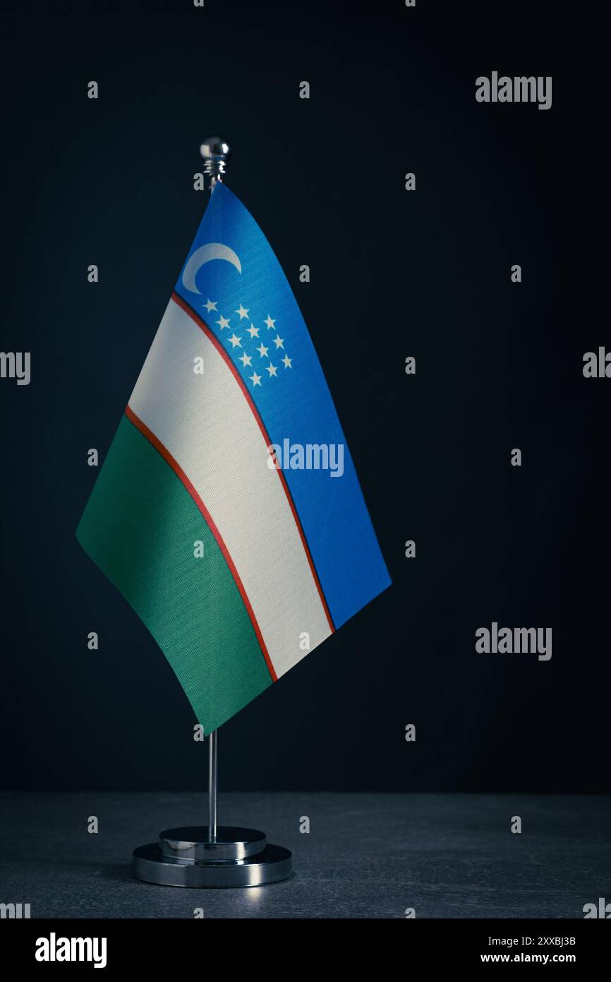 Table flag Uzbekistan on dark background, representing national pride ...