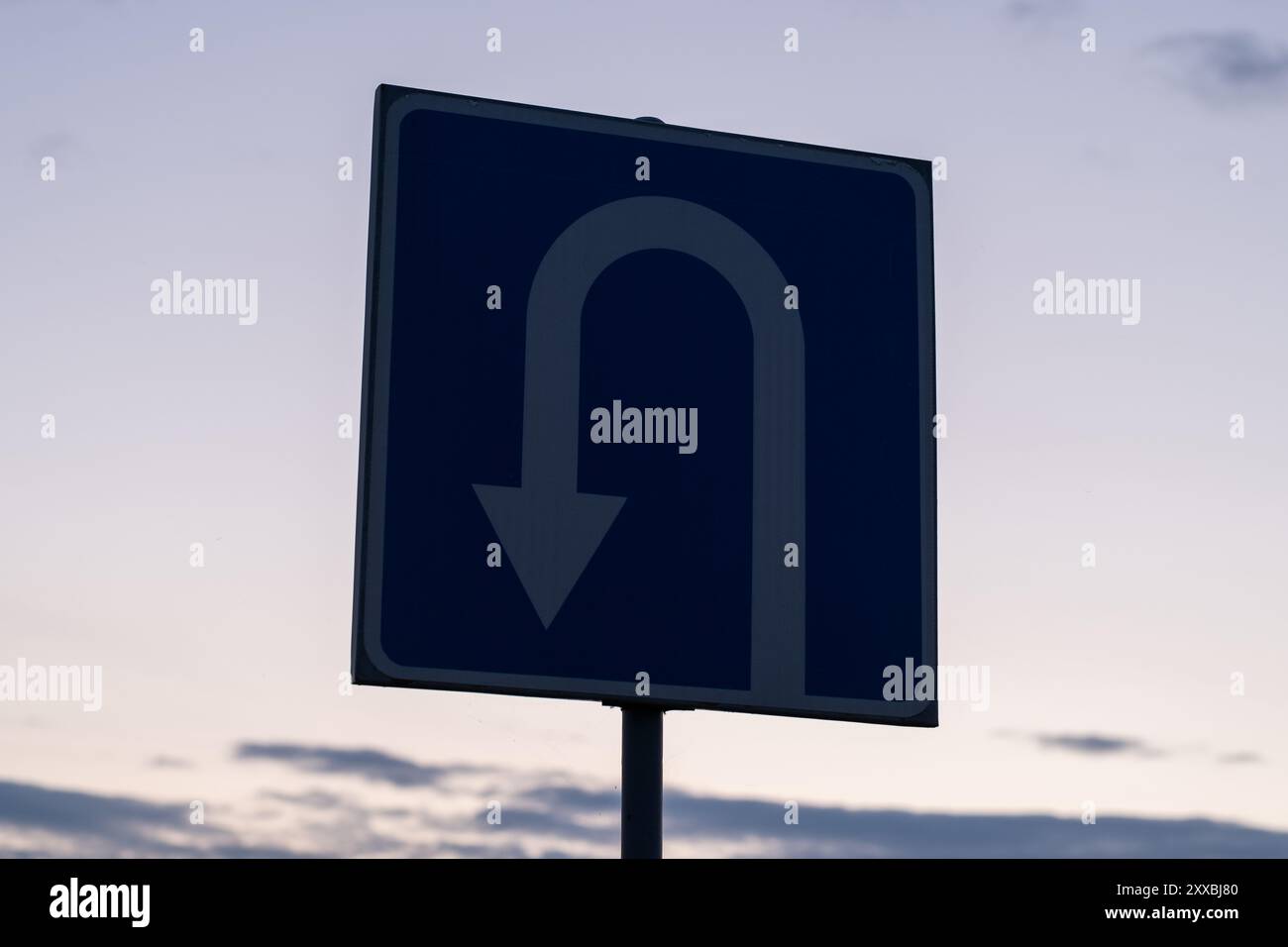 Road sign indicating direction movement in evening sky Stock Photo - Alamy