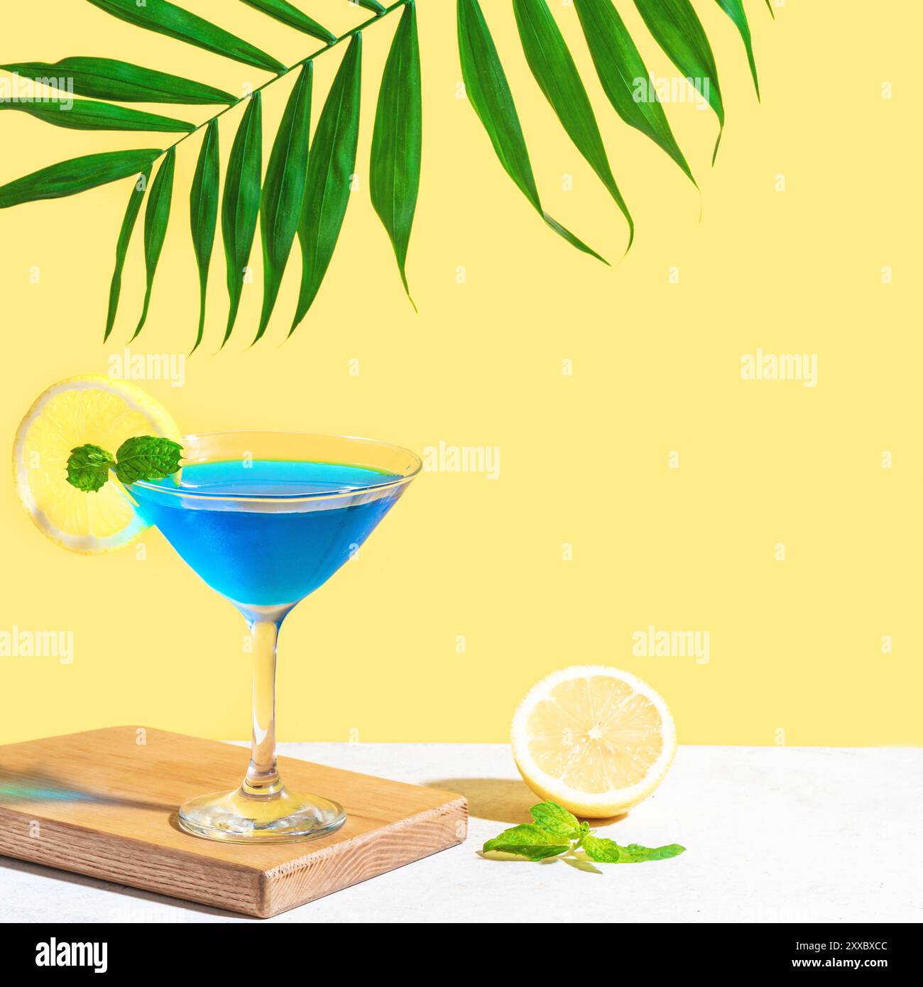 Blue summer cocktail with mint and lemon on bright yellow background ...