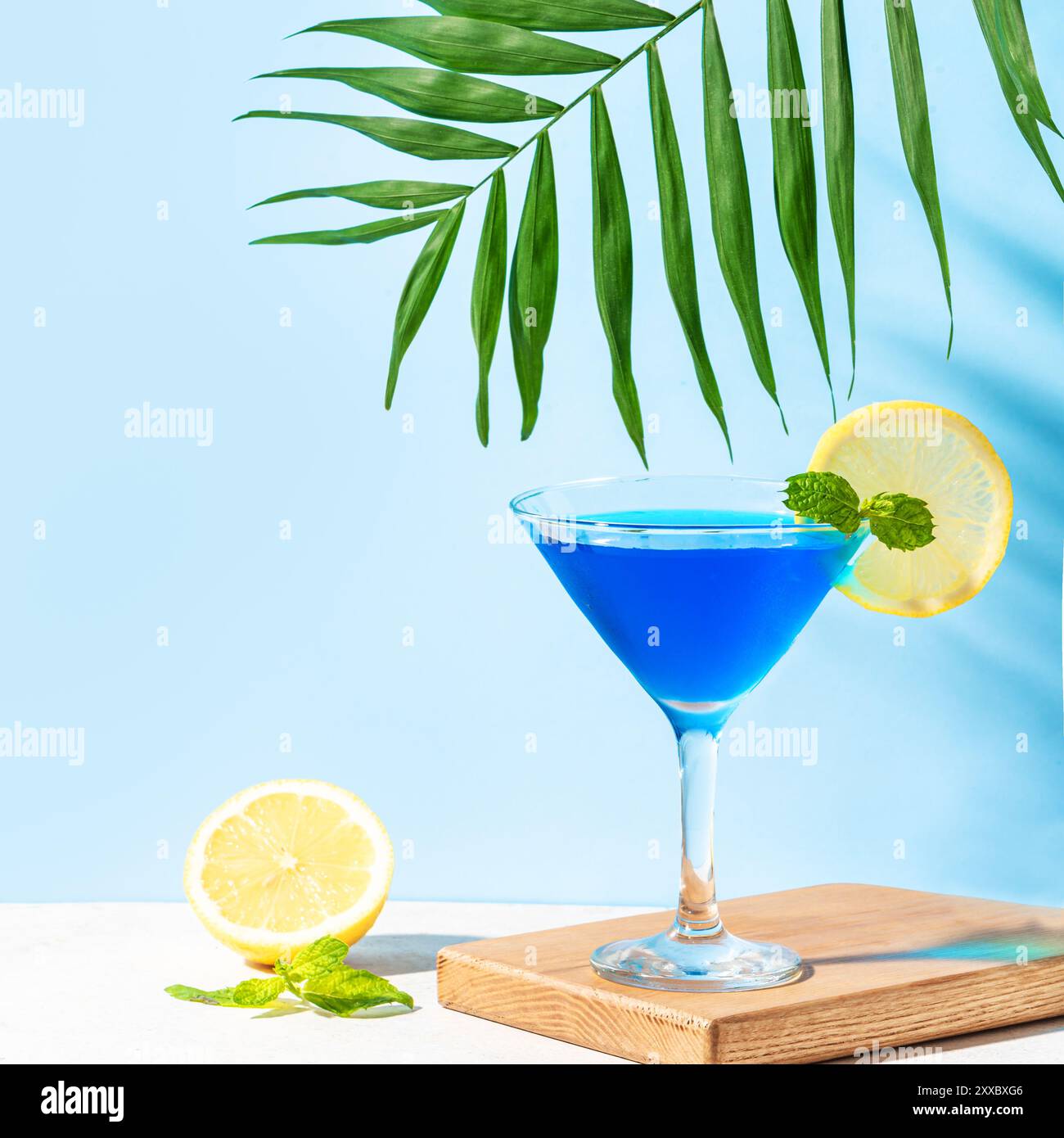 Blue summer cocktail with mint and lemon on sky blue background with ...