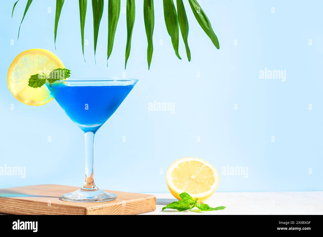 Blue summer cocktail with mint and lemon on sky blue background with ...