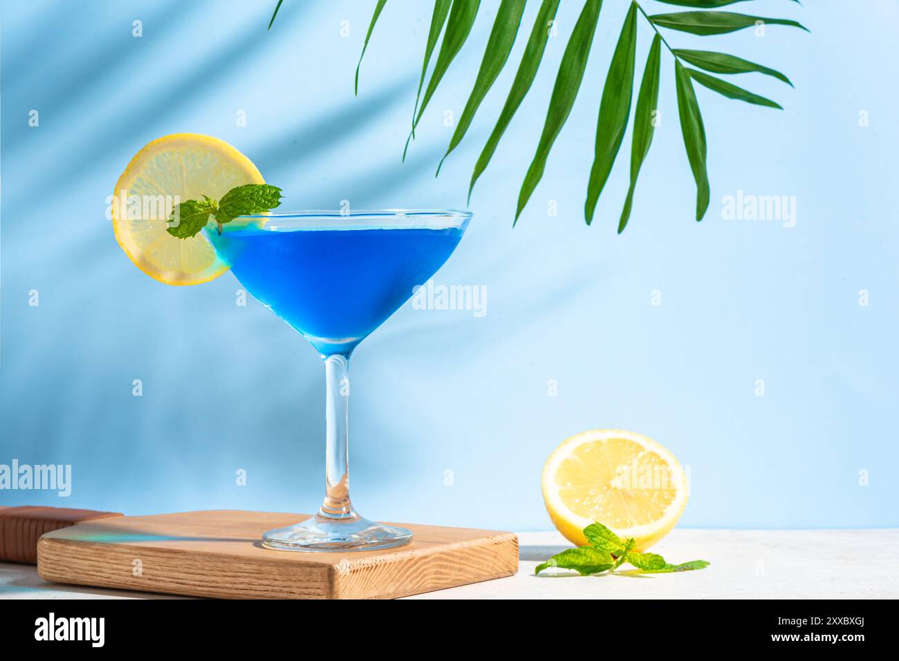 Blue summer cocktail with mint and lemon on sky blue background with ...