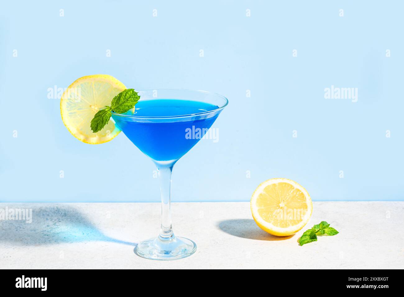 Blue summer cocktail with mint and lemon on light blue background, copy ...