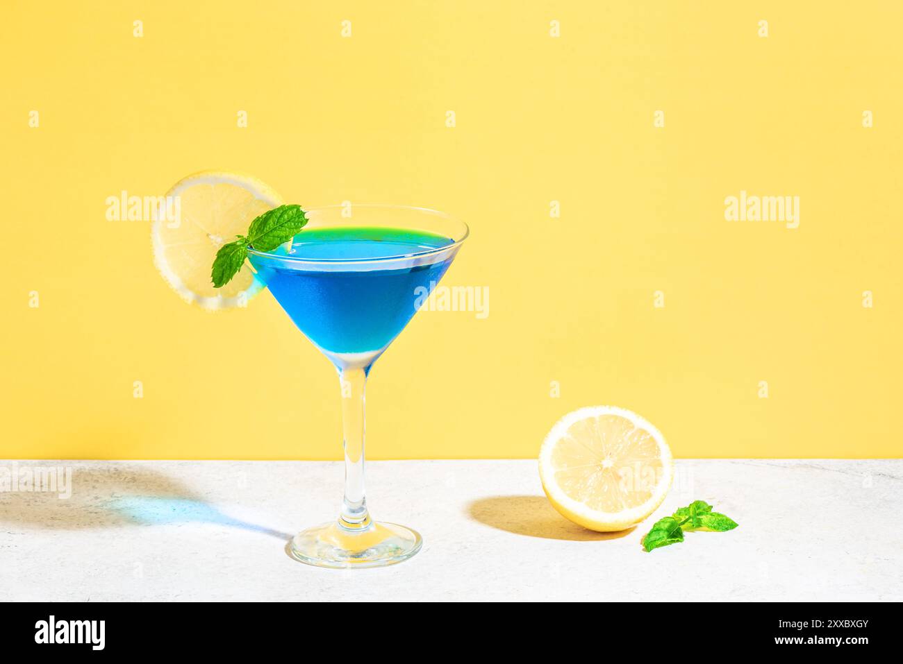 Blue summer cocktail with mint and lemon on bright yellow background ...