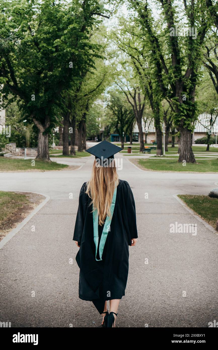 Woman walking down pathway at university during graduation Stock Photo ...