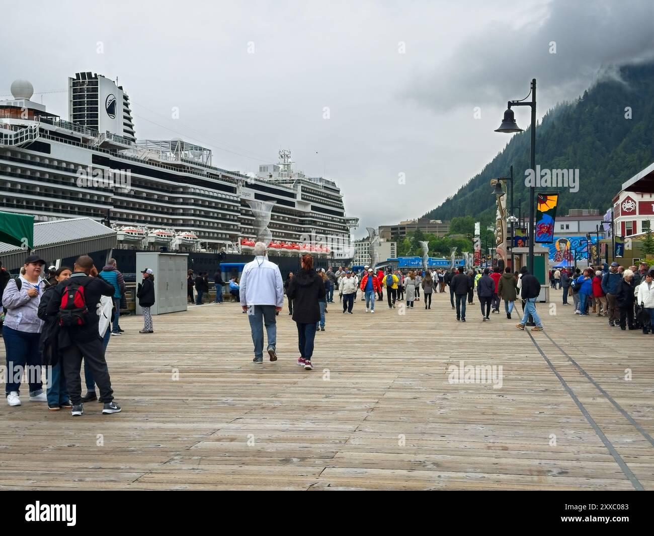 Cruise ship passengers throng the pier at Juneau on an overcast, misty ...