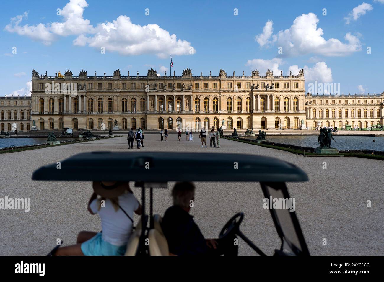 Visitors in a golf cart tour the Chateau de Versailles, whose grounds ...