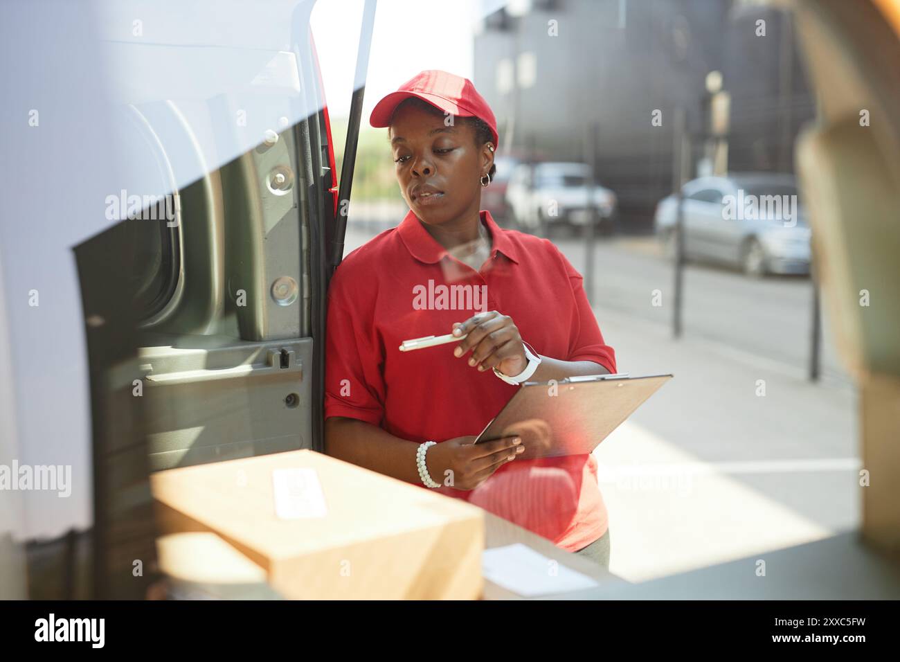 Delivery worker checking information on clipboard while standing next ...