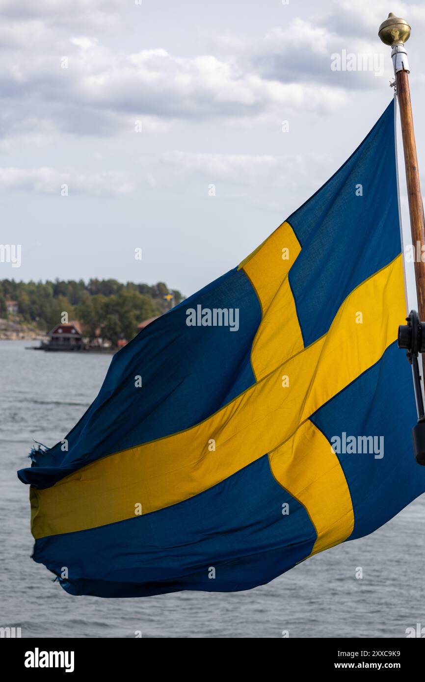 A close-up of the Swedish flag waving in the wind, with a scenic ...