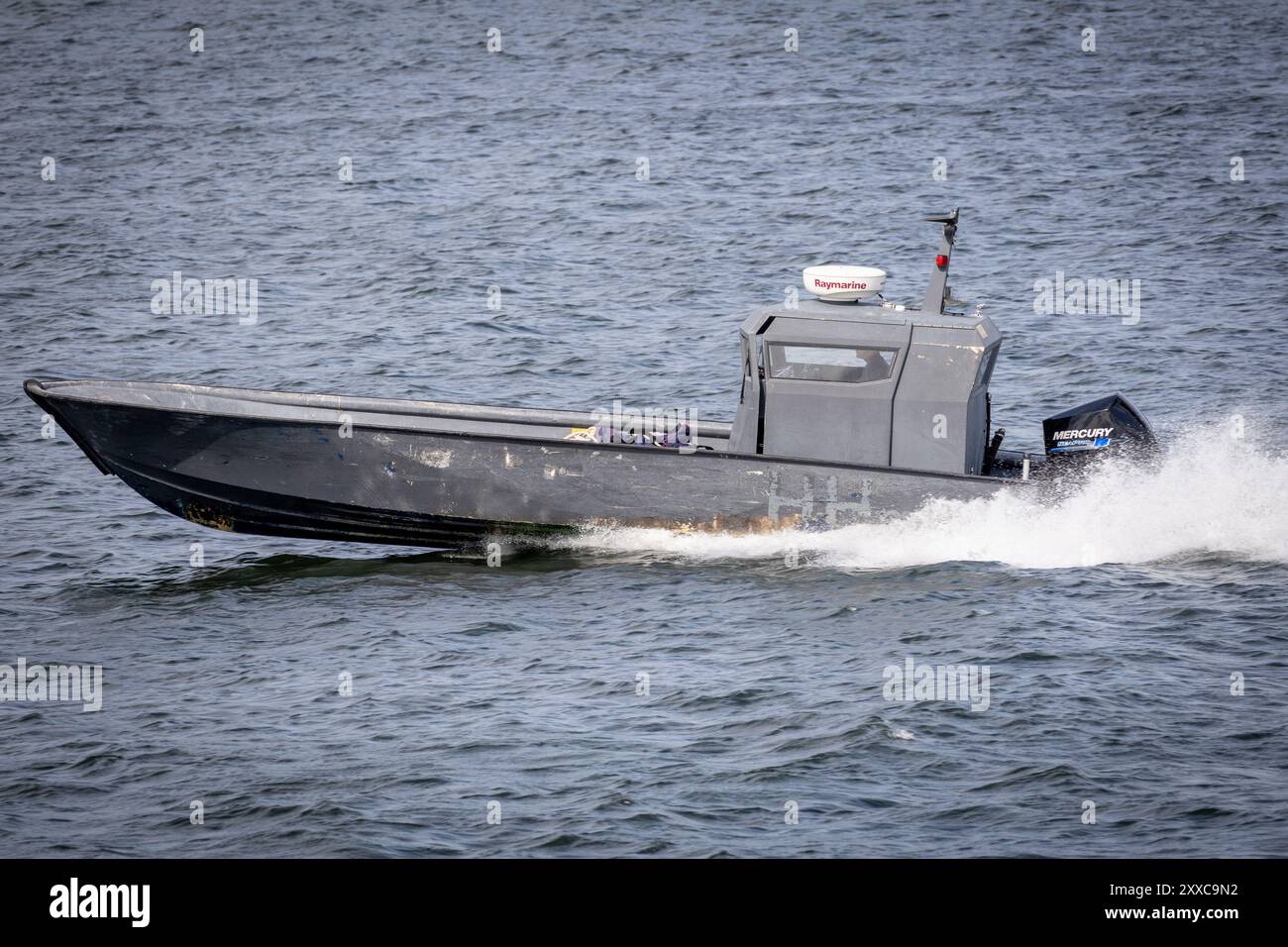 A sleek, gray motorboat speeding across a body of water, creating a ...