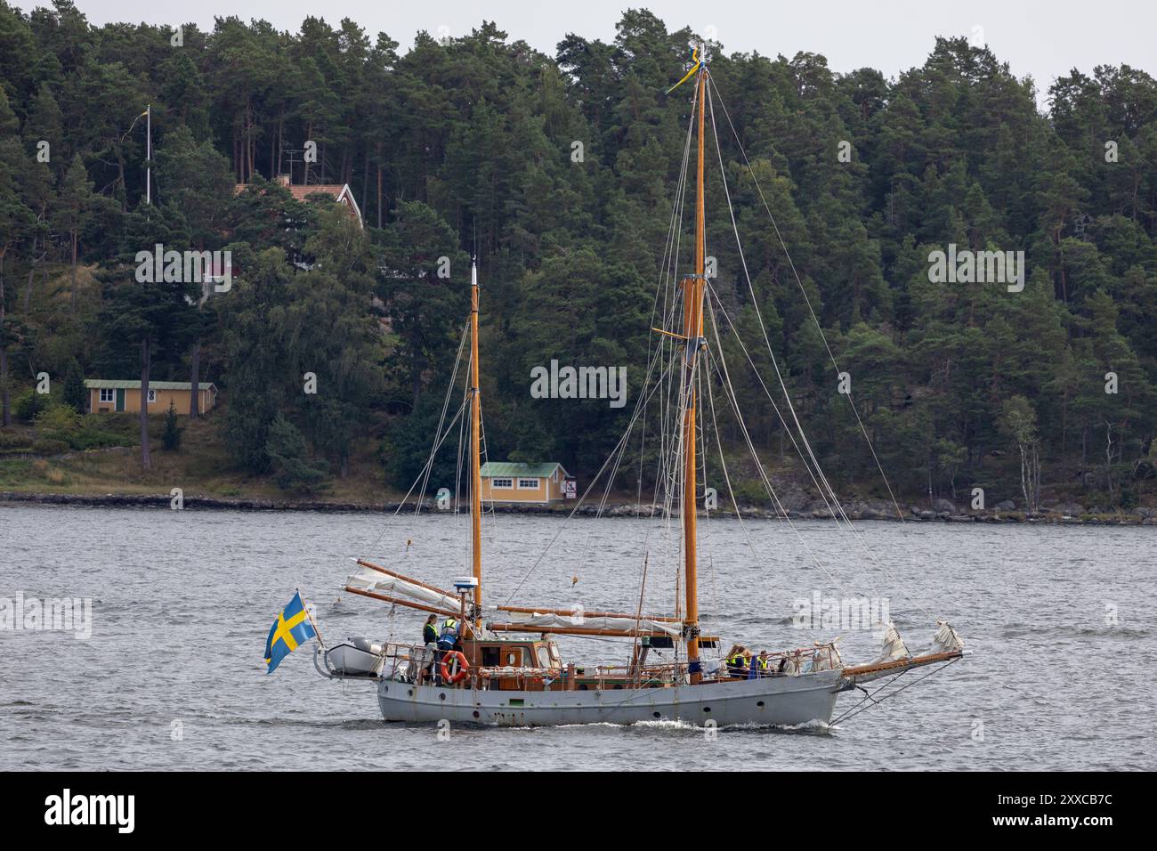 A classic wooden sailing boat named "" with a Swedish flag, navigating ...
