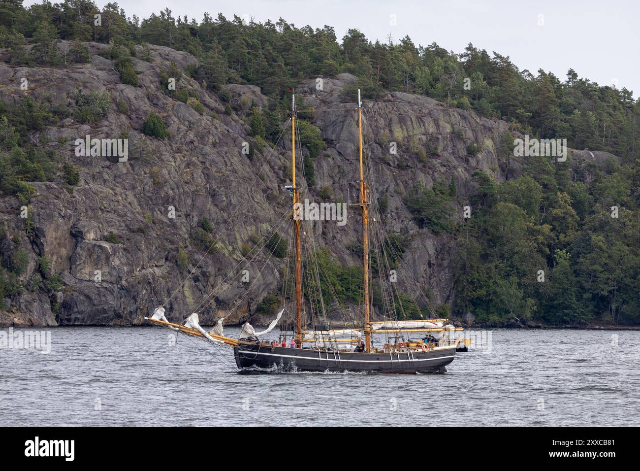 A traditional sailing ship with two masts gliding through calm waters ...