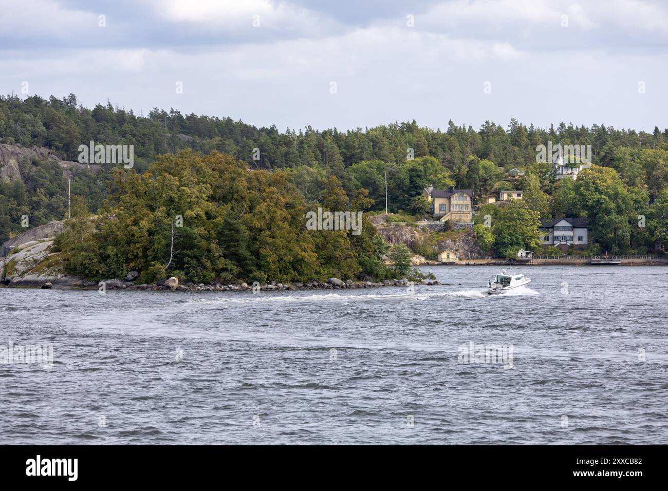 A scenic view of a small island with lush greenery and a boat cruising ...