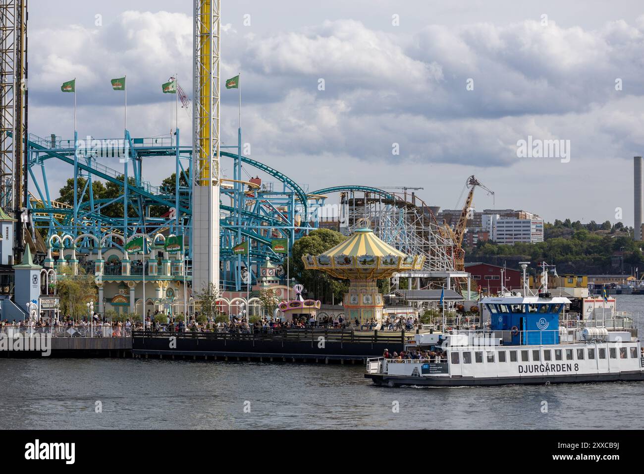 A vibrant amusement park scene by the water featuring a roller coaster ...
