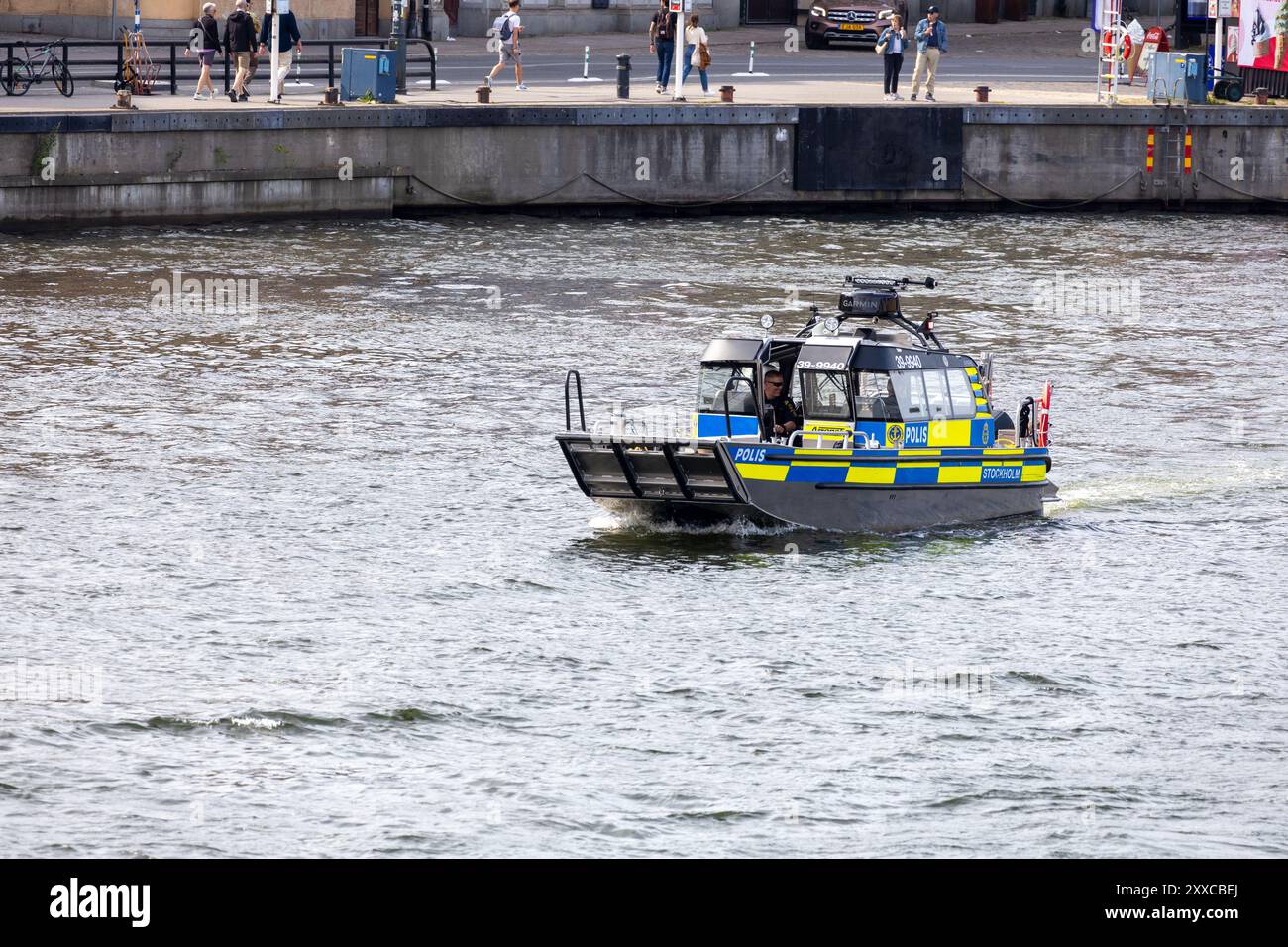 A police boat patrolling a river, with officers on board. The boat is ...