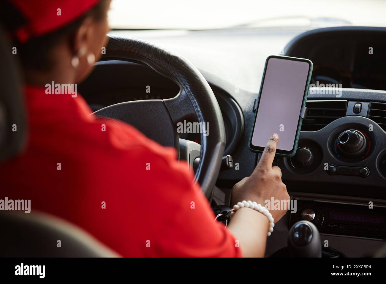 Person in driver's seat holding smartphone with one hand while driving ...