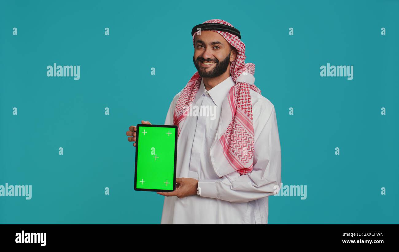 Arab person shows greenscreen display over studio background ...