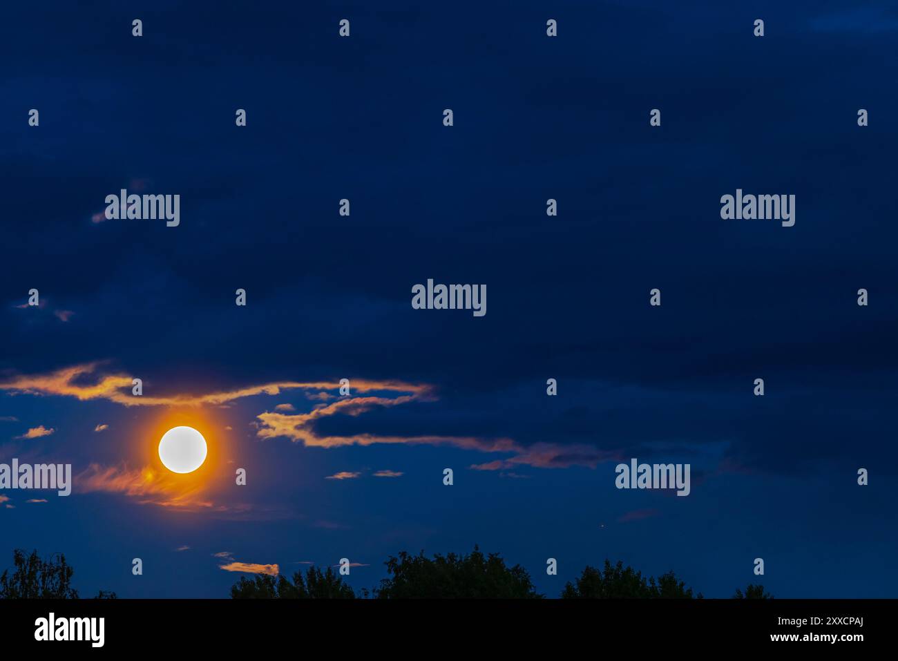 Beautiful view of full moon glowing through dark clouds in night sky ...
