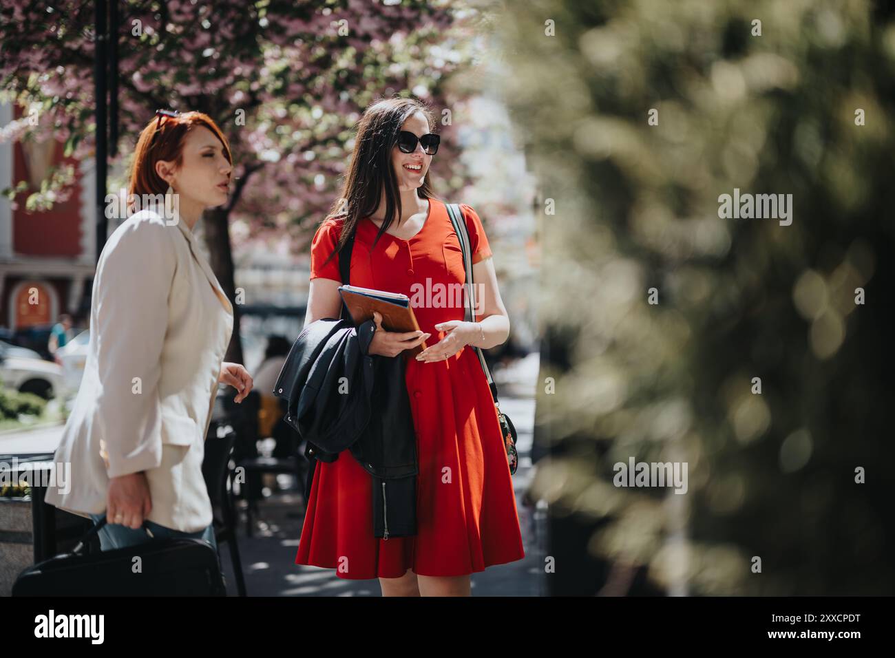 Businesswomen in conversation on a busy city street in springtime Stock ...