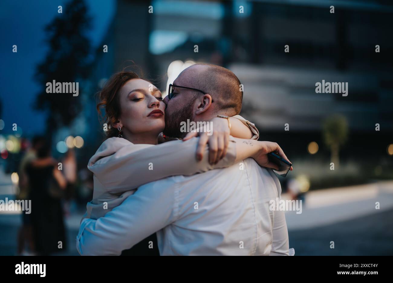 Romantic couple hugging and kissing at night in modern urban setting ...
