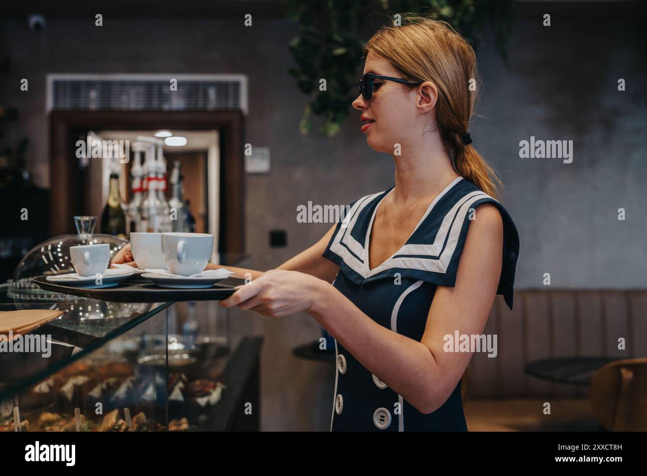 Cafe waitress carrying tray with coffee cups in stylish uniform and ...
