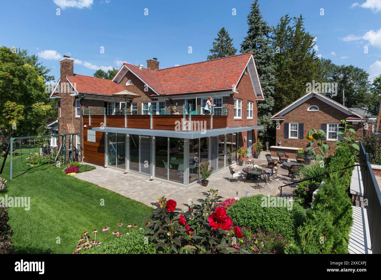 Large brick house with modern glass addition and rooftop deck with ...