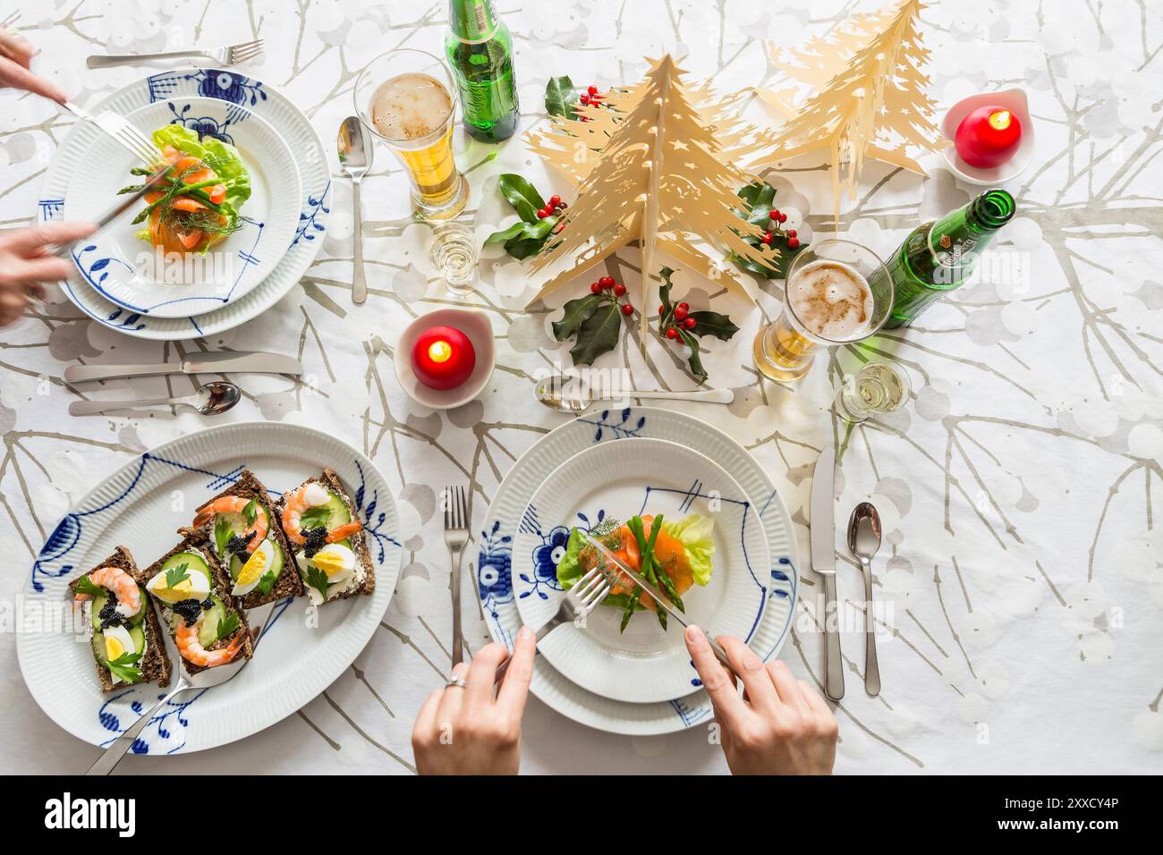 Dining table as viewed from above with two hands eating holiday lunch ...