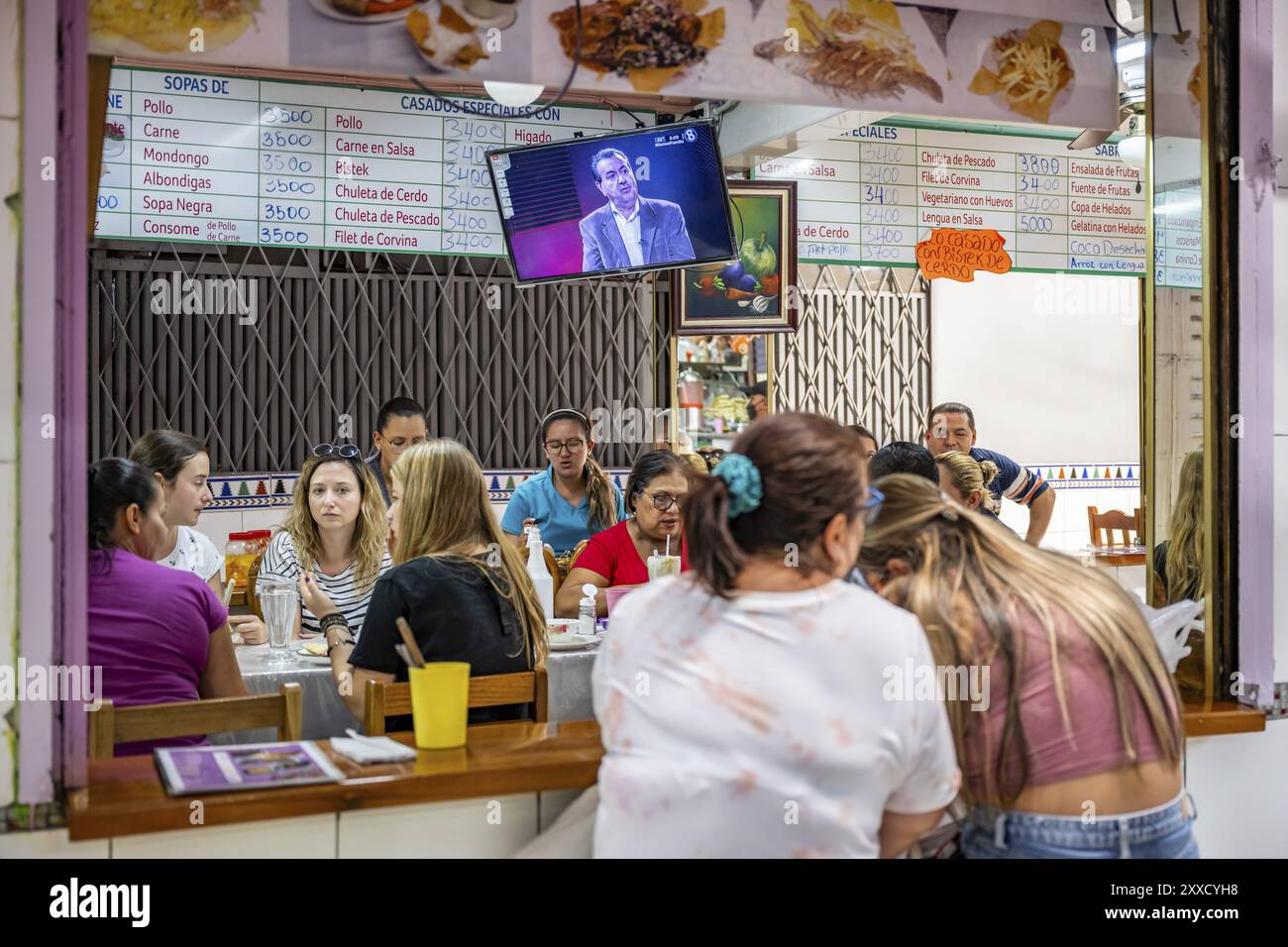 Visitors sitting at a food stall at the counter, Mercado Central de San ...