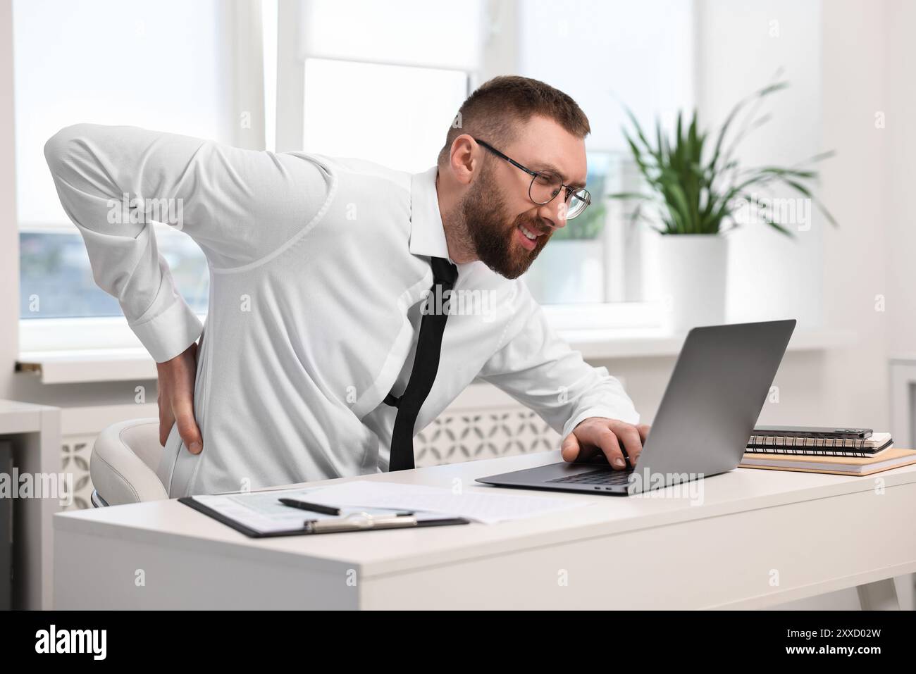 Man suffering from back pain in office. Symptom of poor posture Stock ...