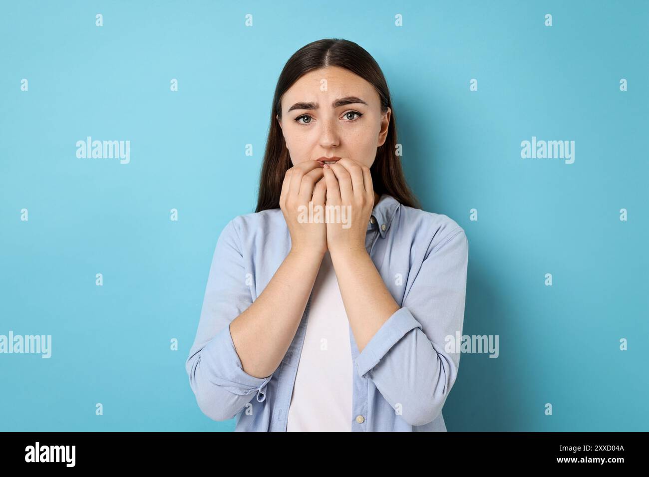 Portrait of scared woman on light blue background Stock Photo - Alamy
