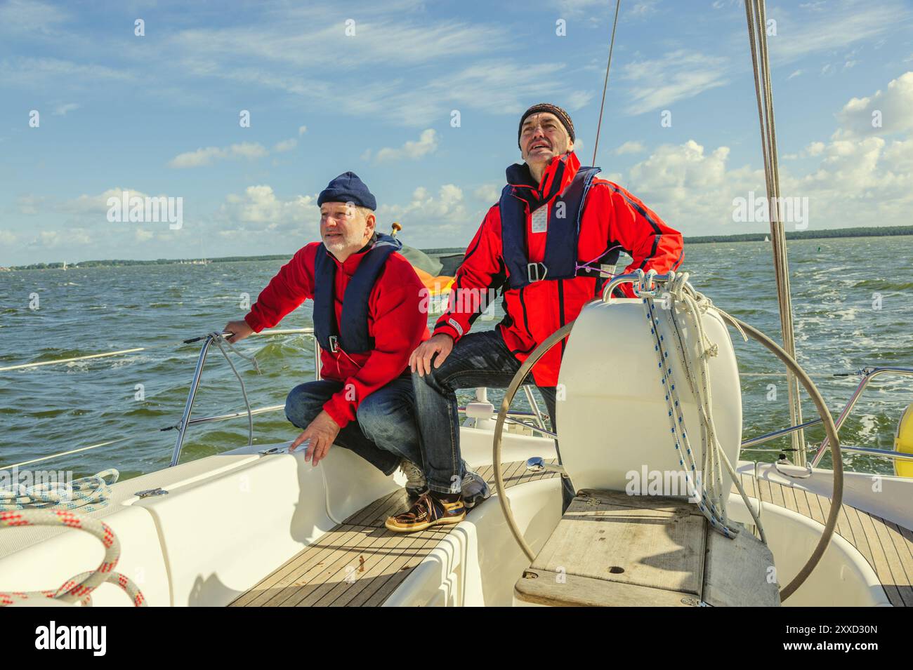 Two men in red jackets stand at the stern of a sailing yacht Stock ...