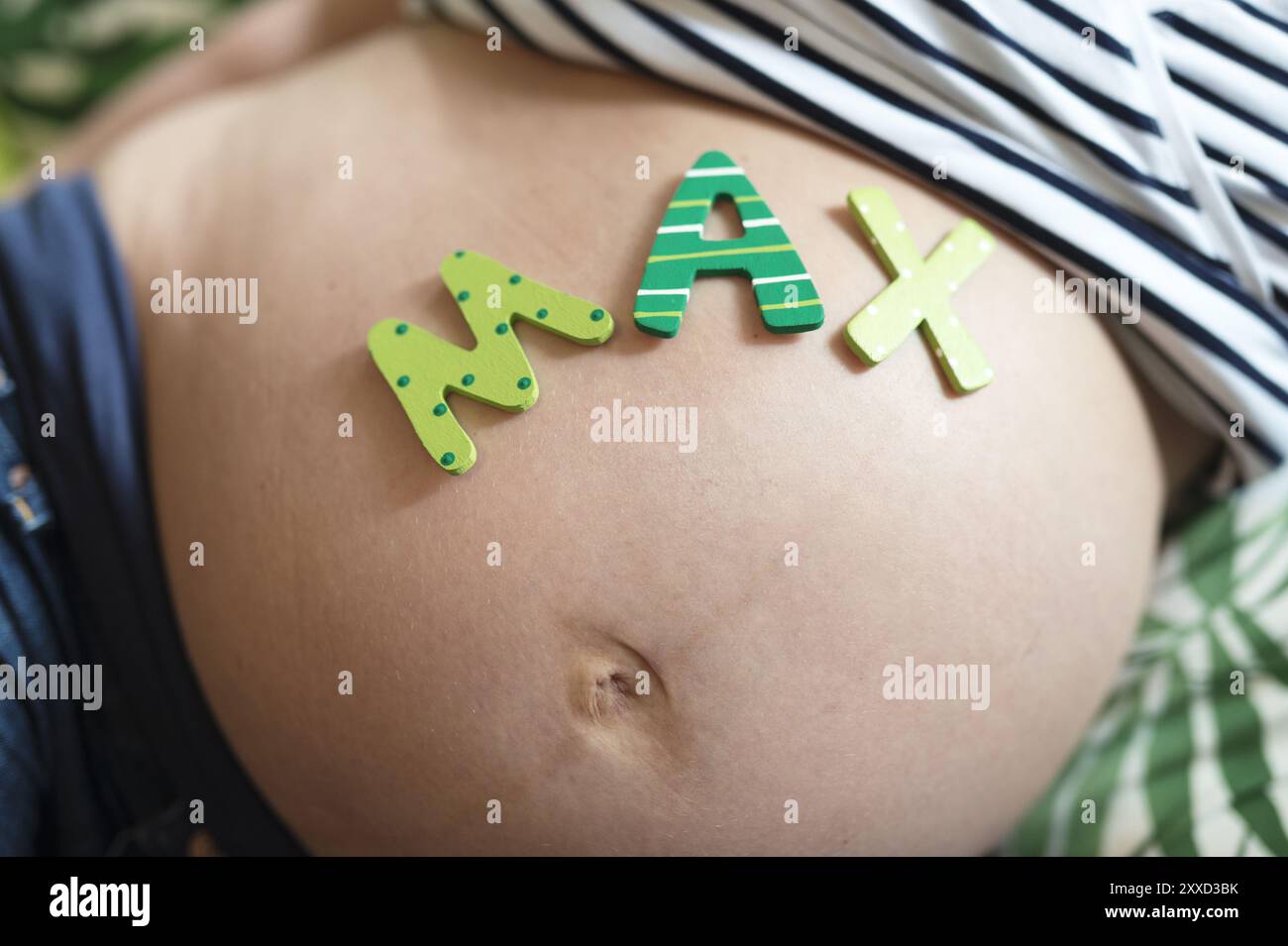 Baby bump at 9 months with the child's name formed from wooden letters ...