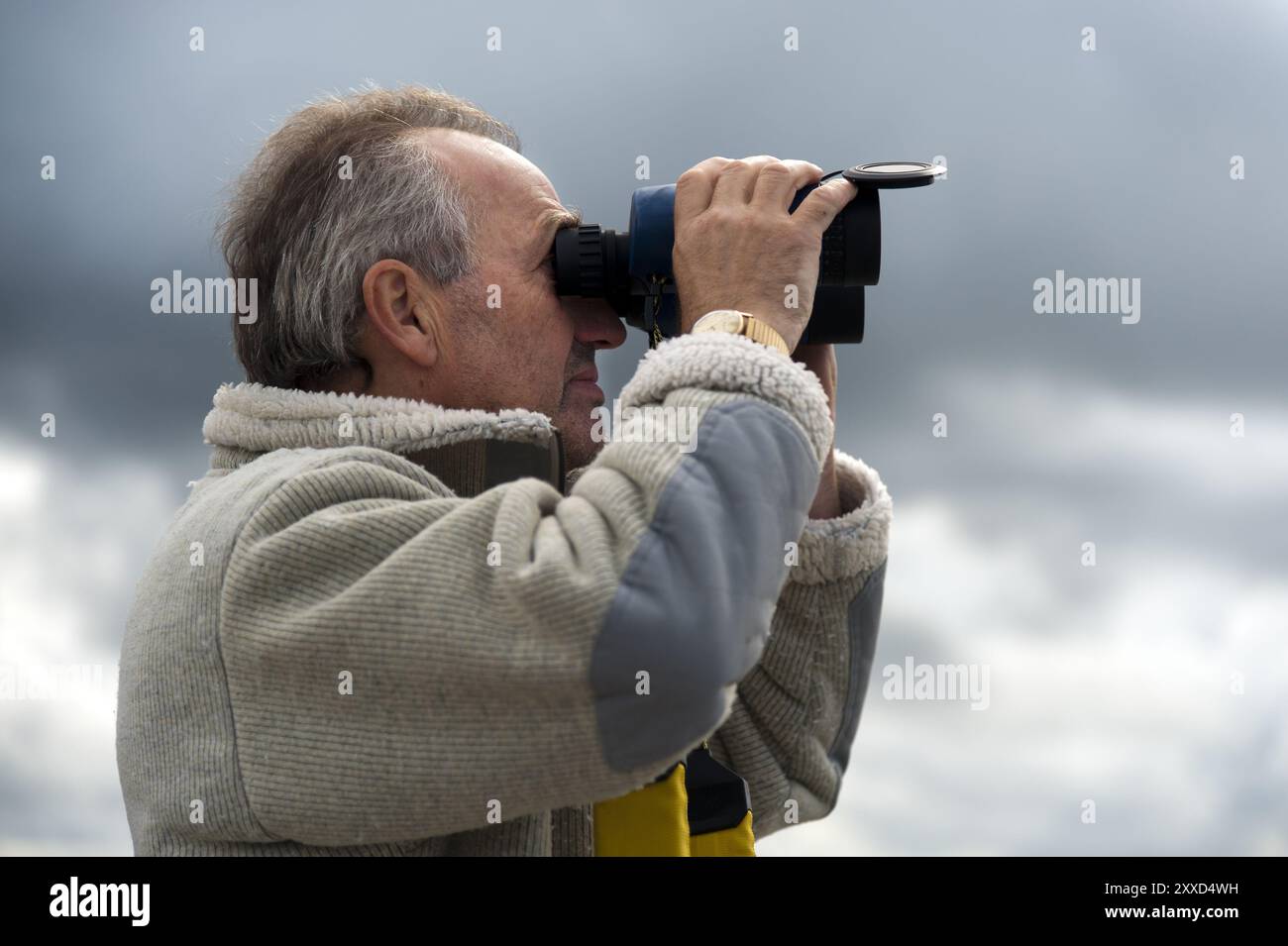 Man in side view looking through binoculars Stock Photo - Alamy
