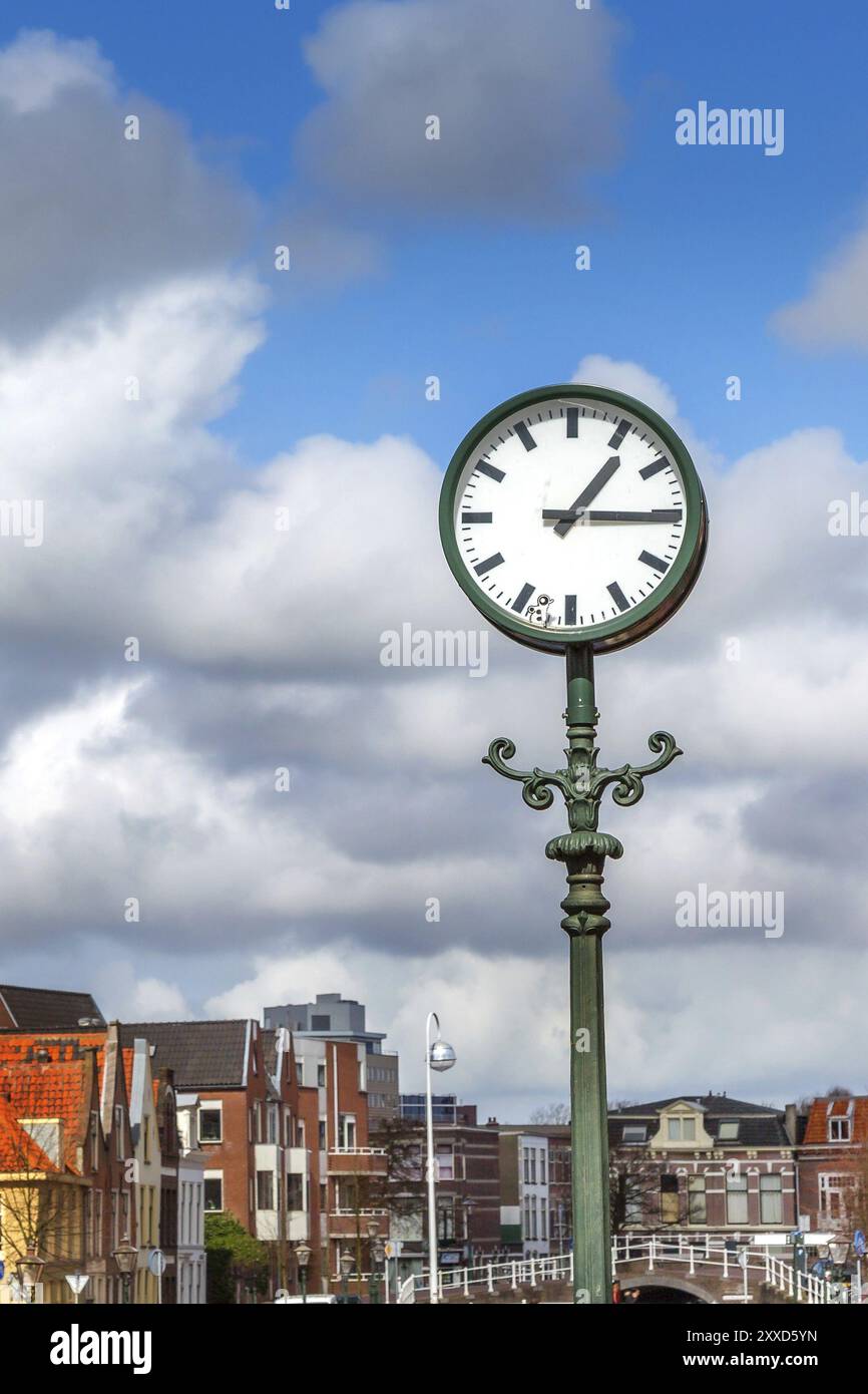 Street clock and traditional dutch houses against blue cloudy sky in ...
