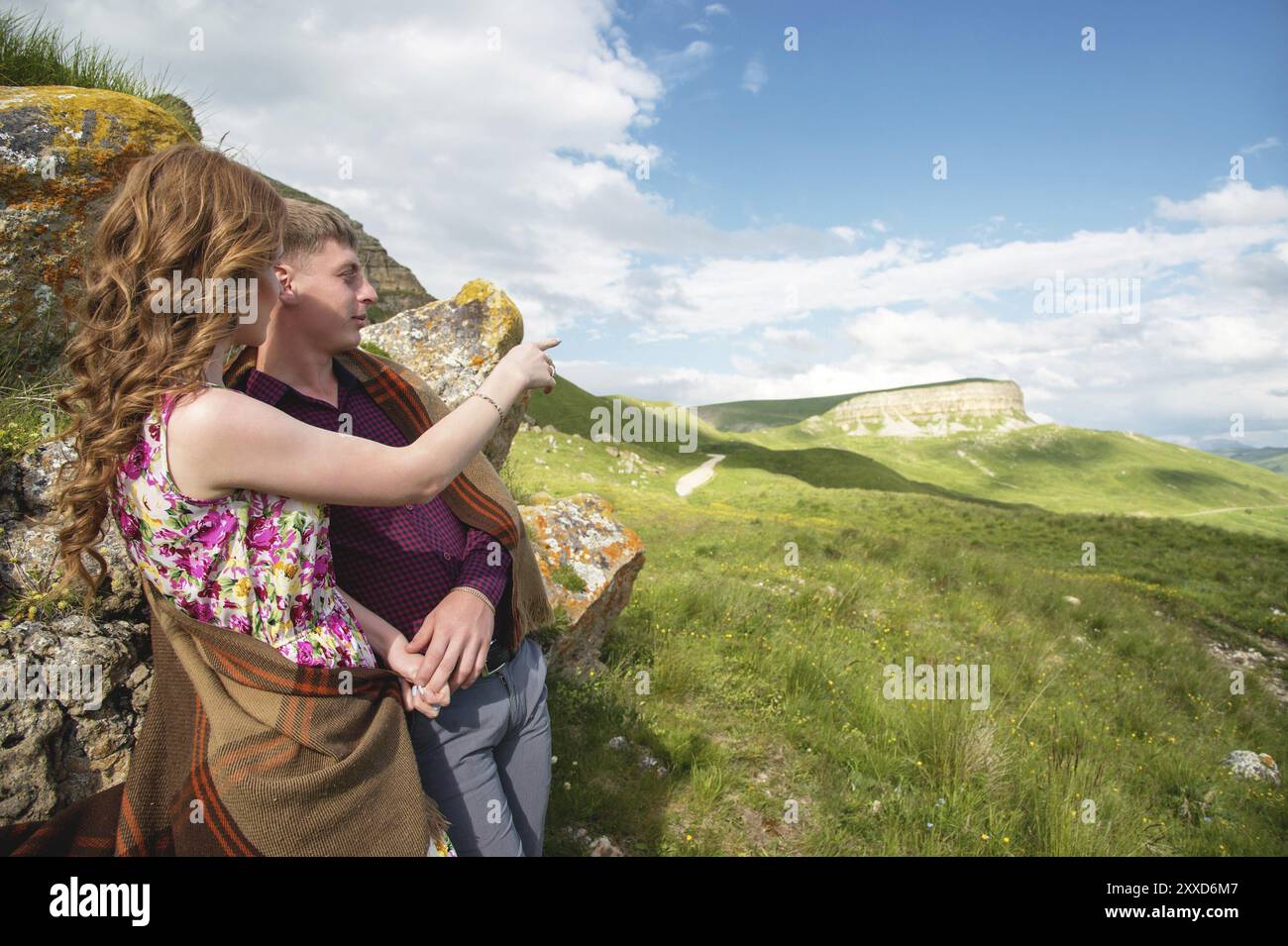 Young married couple on nature stand and hold hands and the girl points ...