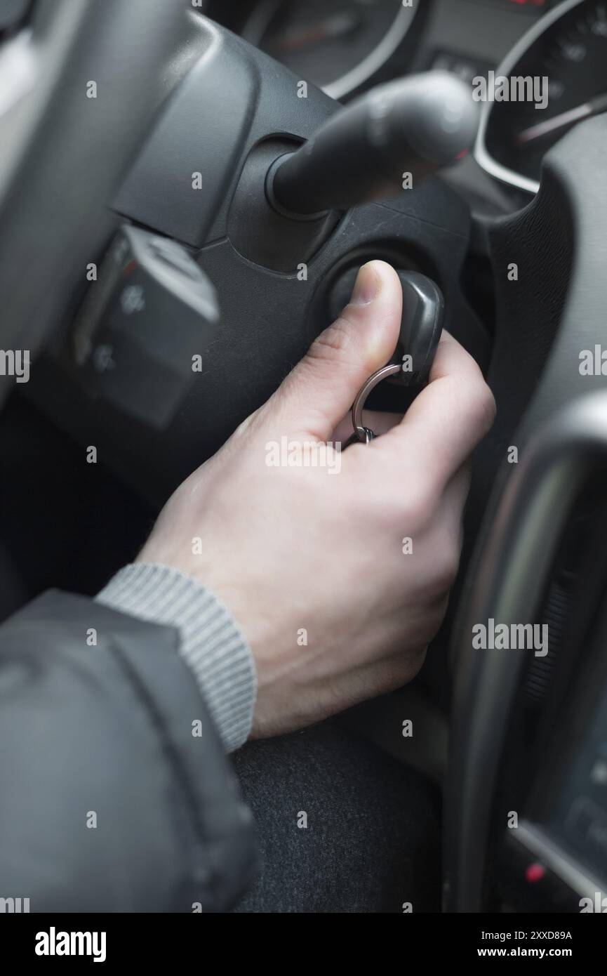 Closeup inside vehicle of hand holding key in ignition, steering wheel ...